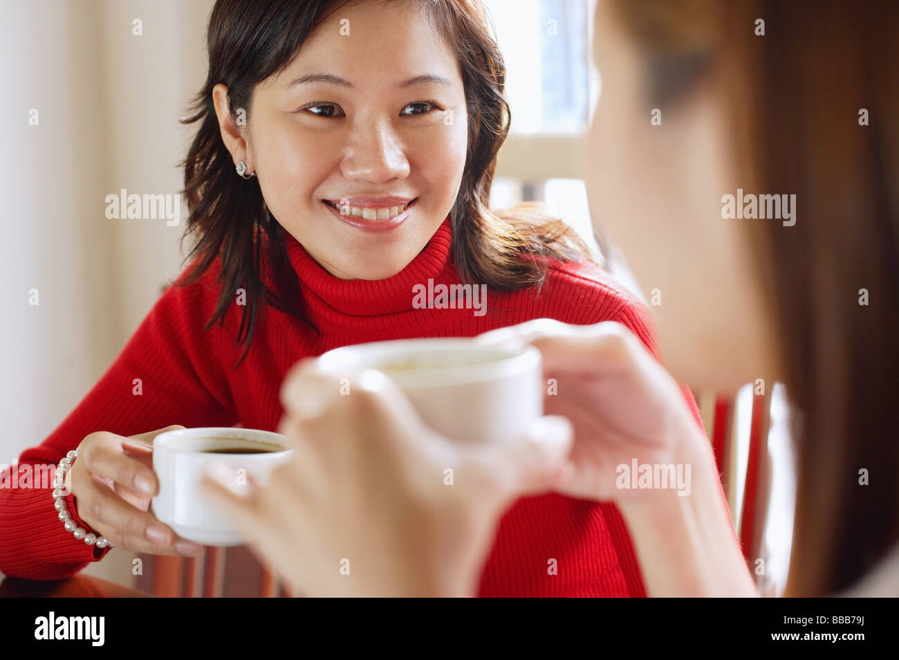 Women holding cups, sitting face to face Stock Photo - Alamy