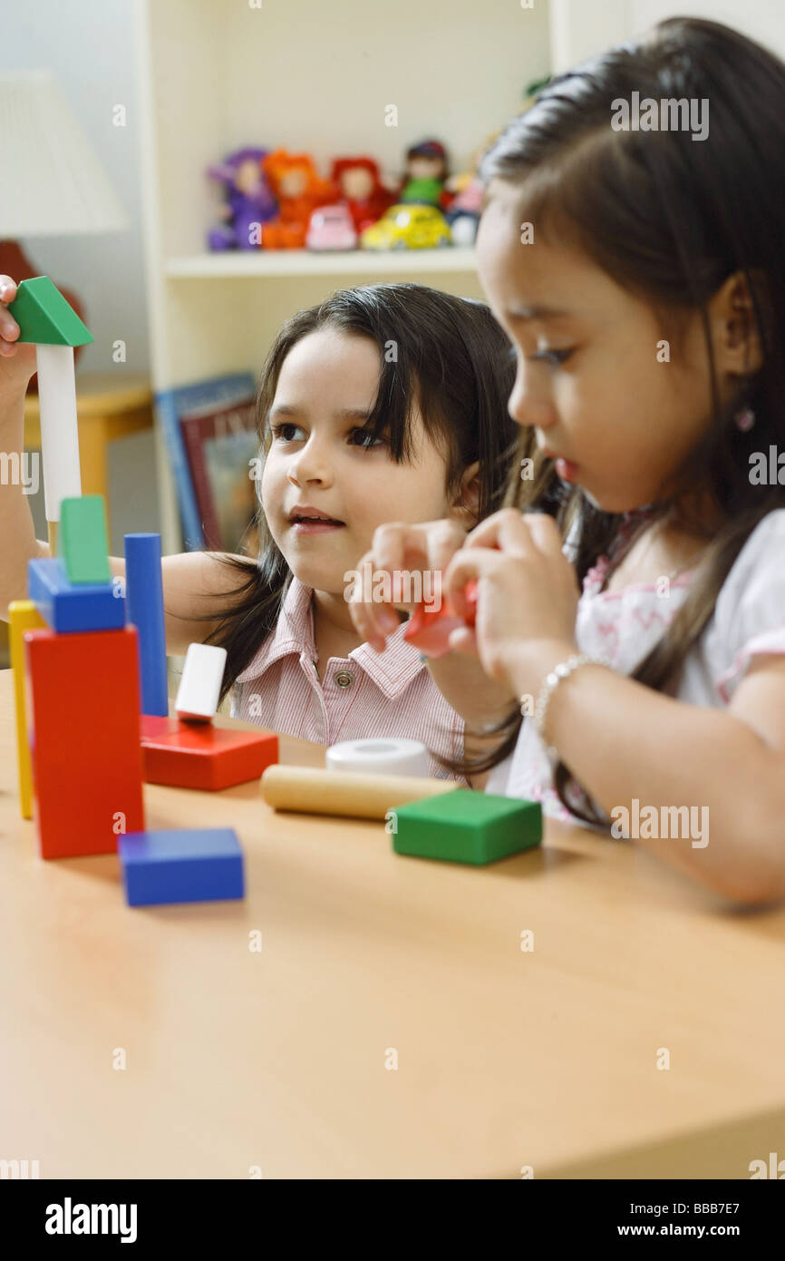 Two girls side by side, playing with building blocks Stock Photo - Alamy