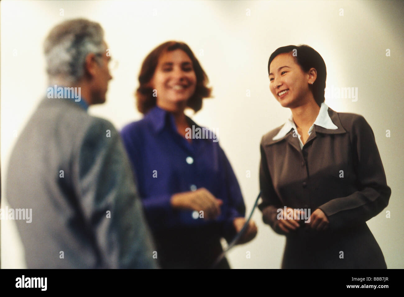 Asian female executive talking with two Caucasian executives Stock ...
