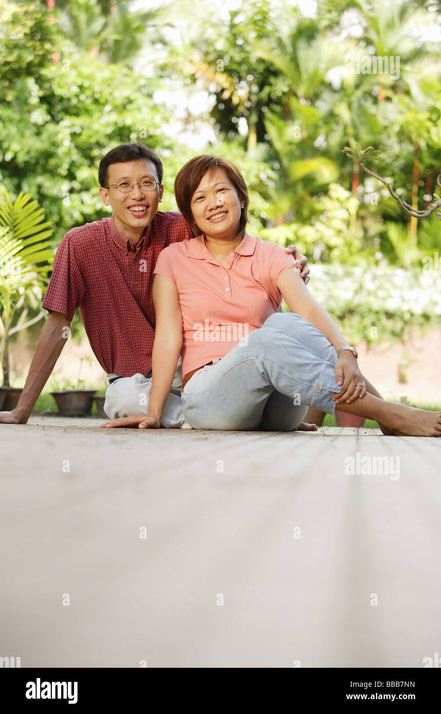 Couple sitting on floor, side by side, looking at camera Stock Photo ...
