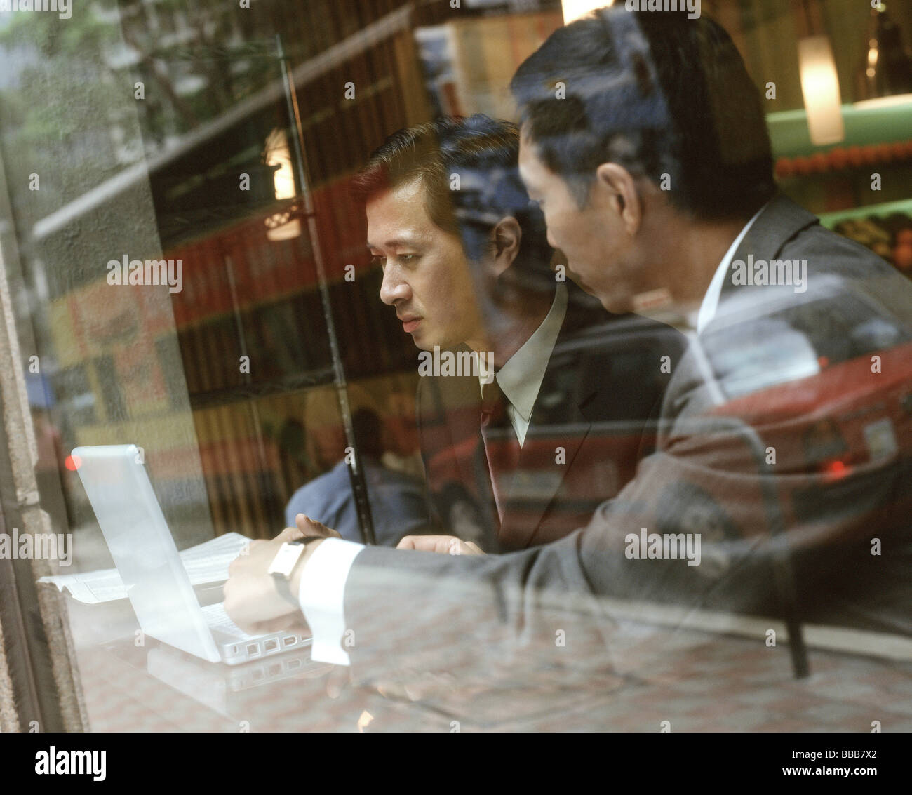 Male executives using laptop seen through glass window Stock Photo - Alamy