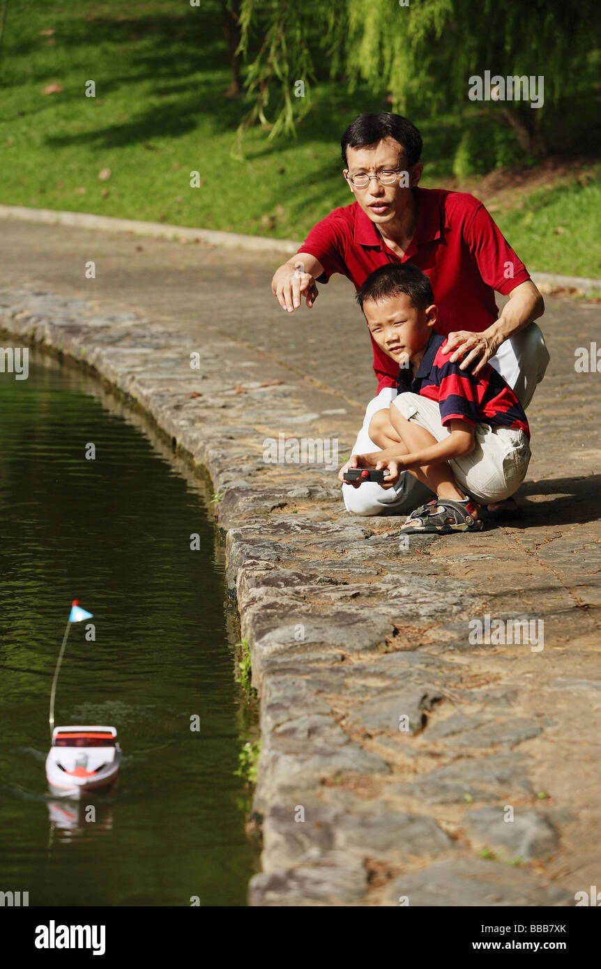 Father and son playing with remote control boat Stock Photo - Alamy