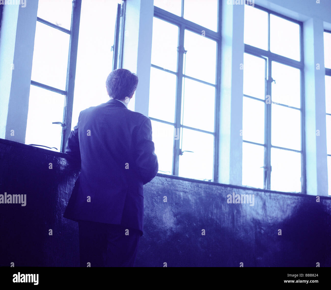 Executive with back to camera looking out window Stock Photo - Alamy