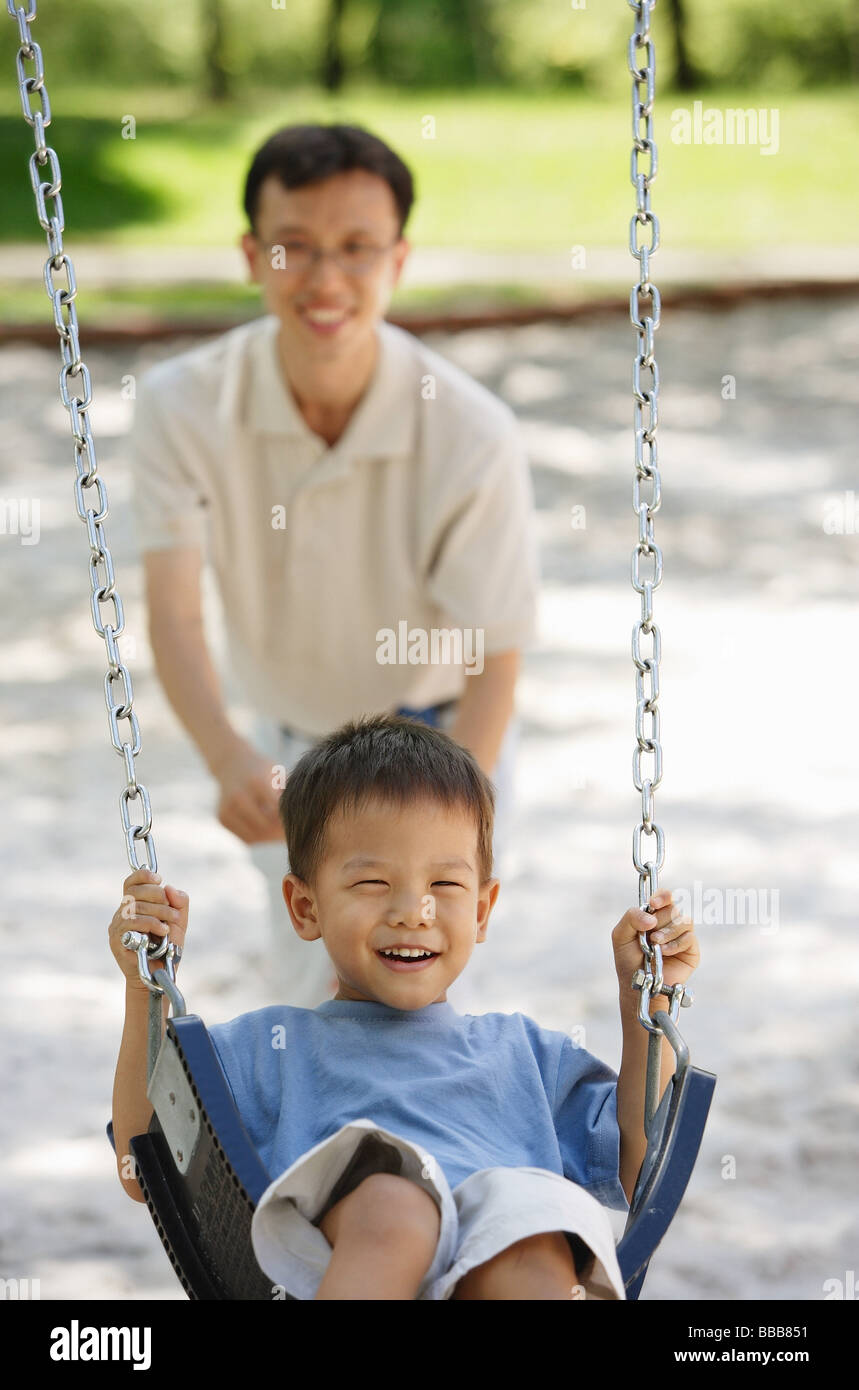 Boy on swing, father pushing him Stock Photo - Alamy