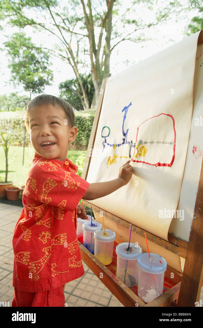 Boy pointing at drawing on easel, looking over shoulder, smiling Stock ...