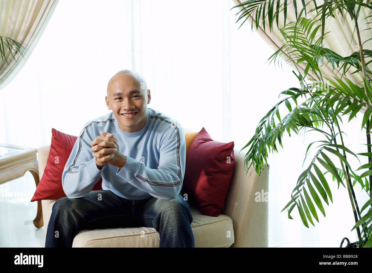 Man sitting on sofa and smiling hi-res stock photography and images - Alamy