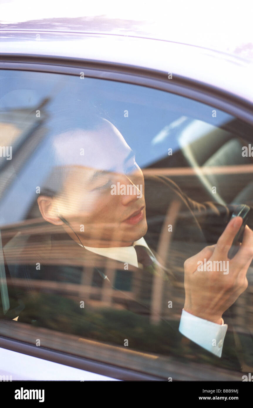 Male executive holding cellular phone hands-free set in car Stock Photo ...