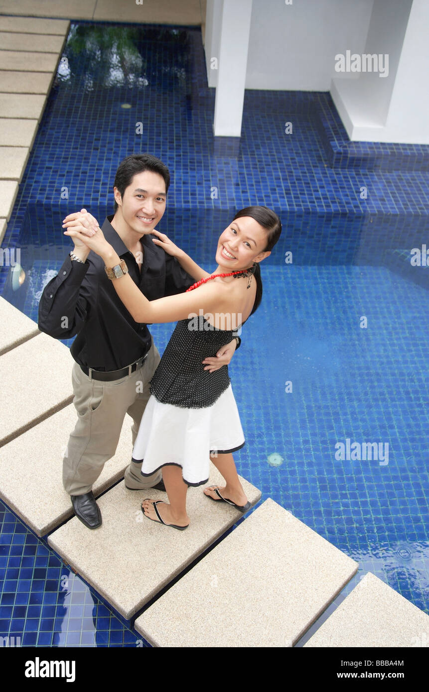 Couple dancing by swimming pool, smiling at camera Stock Photo - Alamy