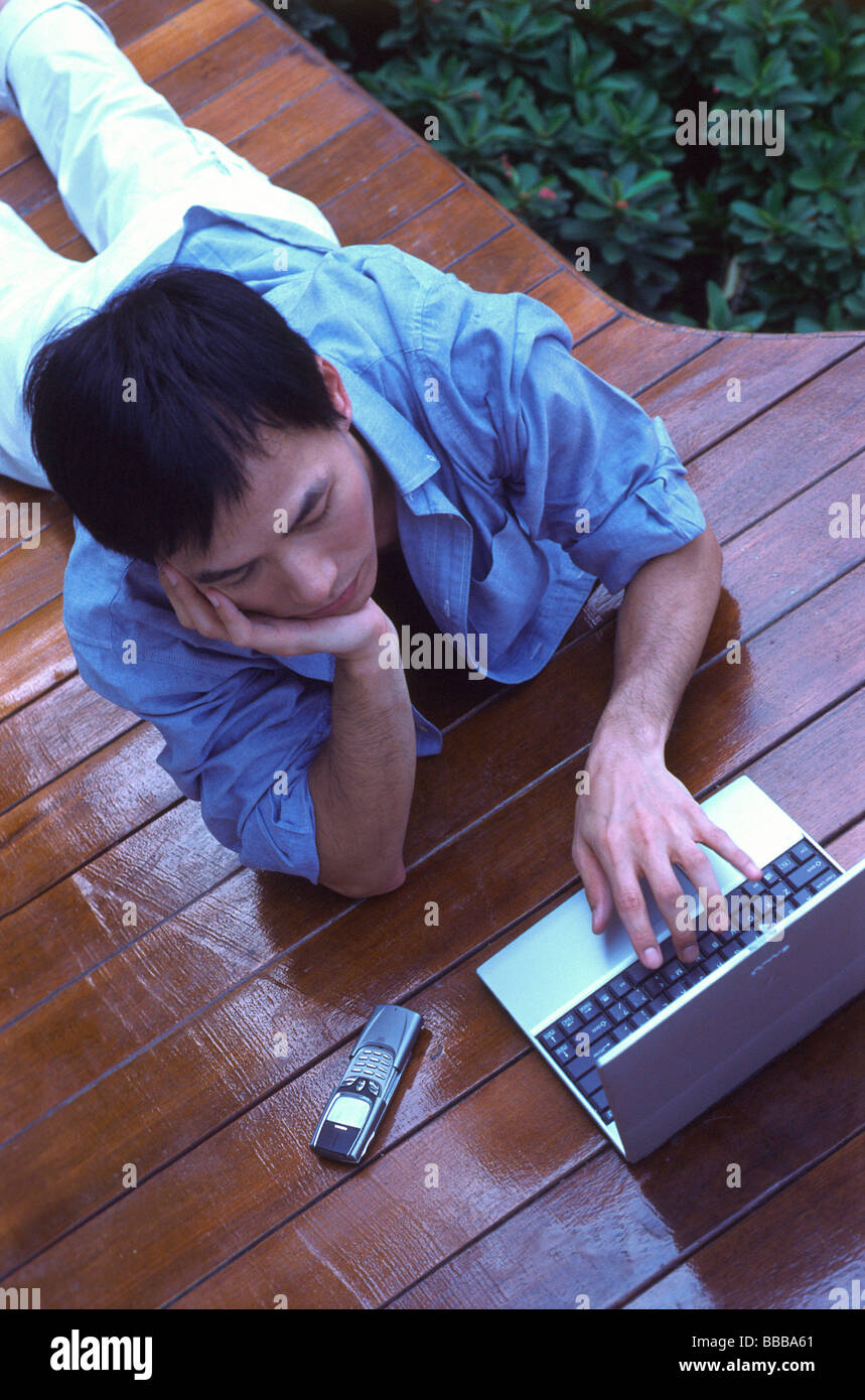 Young man lying on floor, using laptop Stock Photo - Alamy