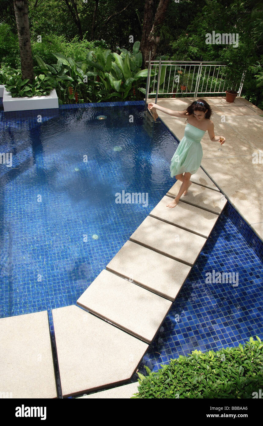 Woman in green dress walking across swimming pool Stock Photo - Alamy