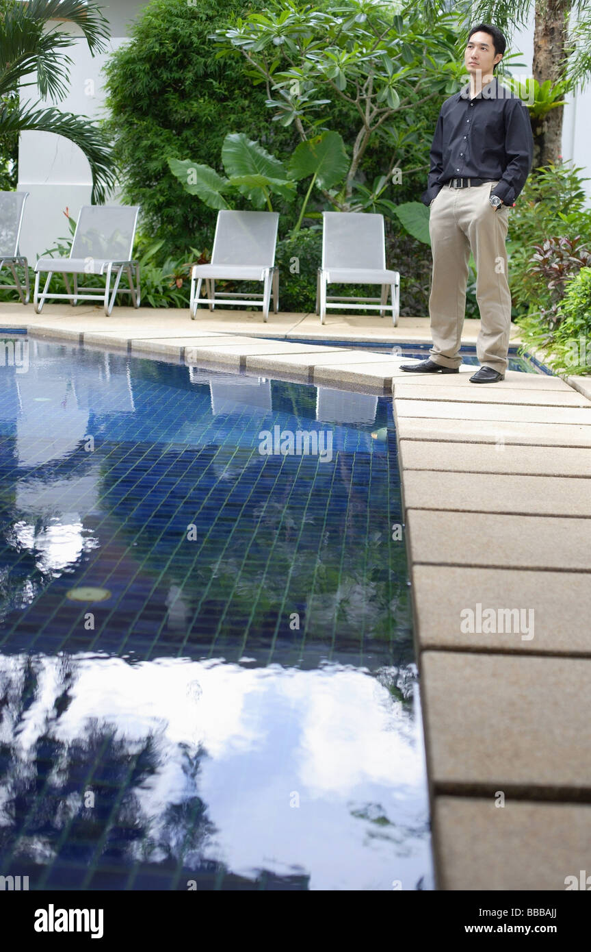 Man standing by swimming pool, hands in pocket Stock Photo - Alamy