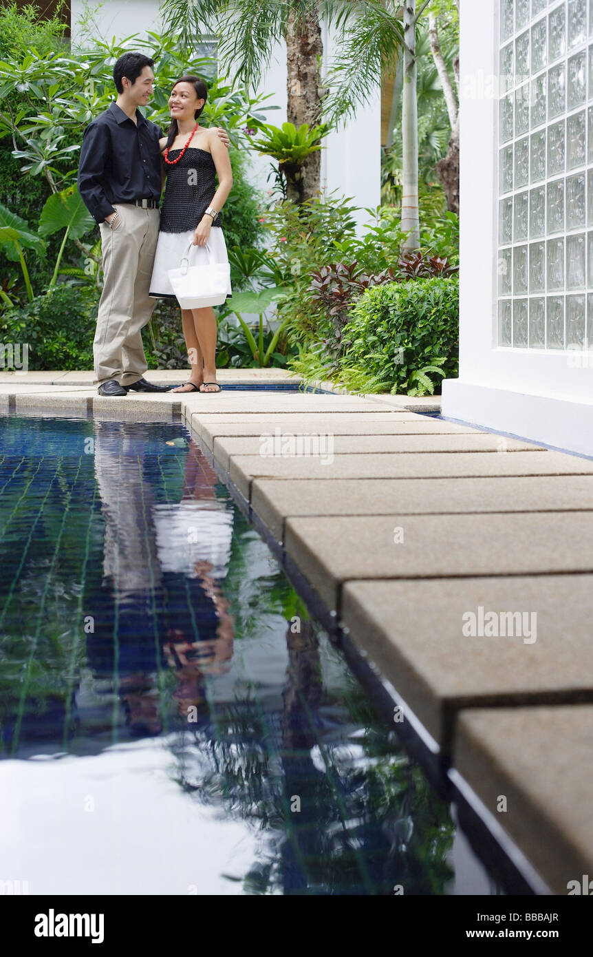 Couple standing side by side next to swimming pool Stock Photo - Alamy