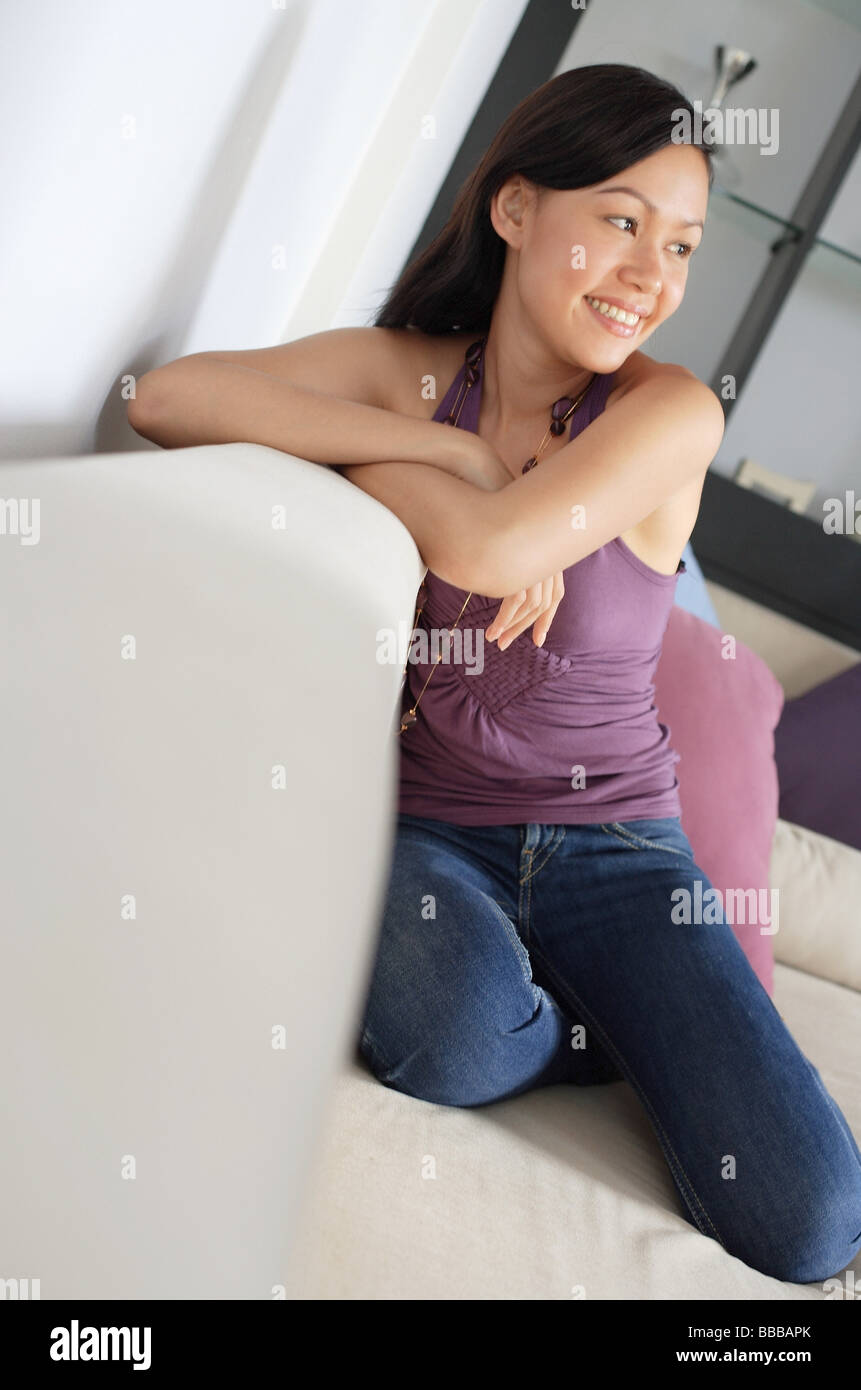 Woman sitting, leaning on back of sofa, looking away Stock Photo - Alamy