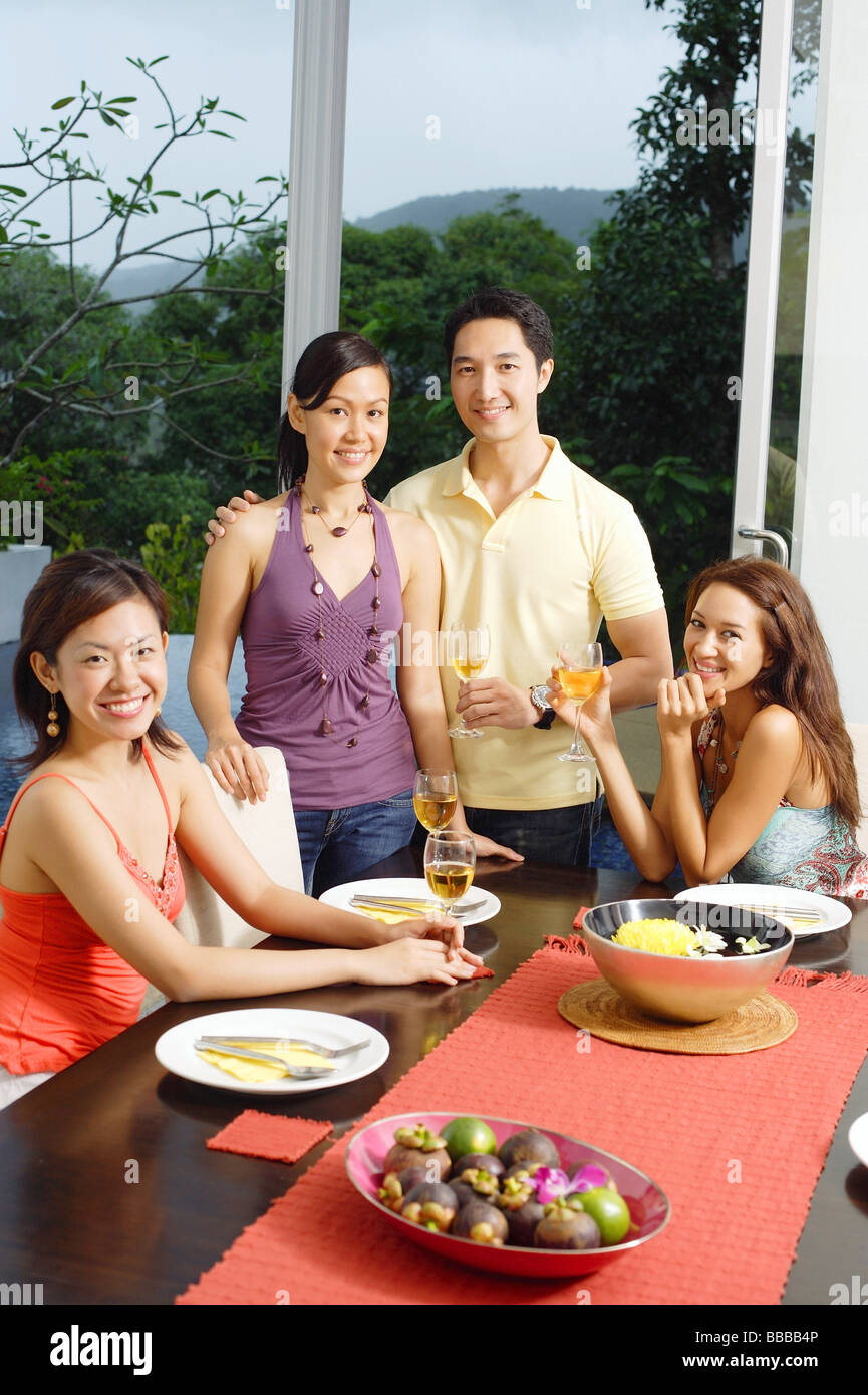 Young adults around dinner table, smiling at camera Stock Photo - Alamy