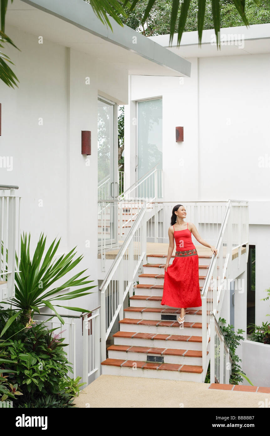 Woman in red dress walking down stairs Stock Photo - Alamy