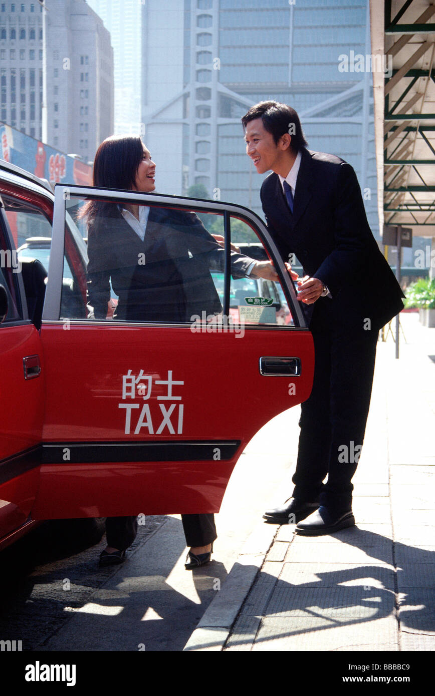 Female executive getting into taxi, male executive holding door Stock ...