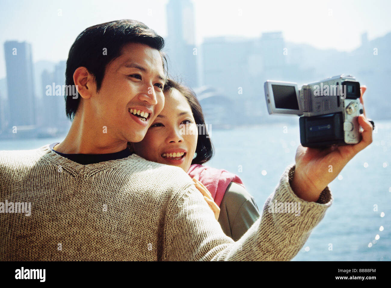 Couple by waterfront, man holding video camera Stock Photo - Alamy