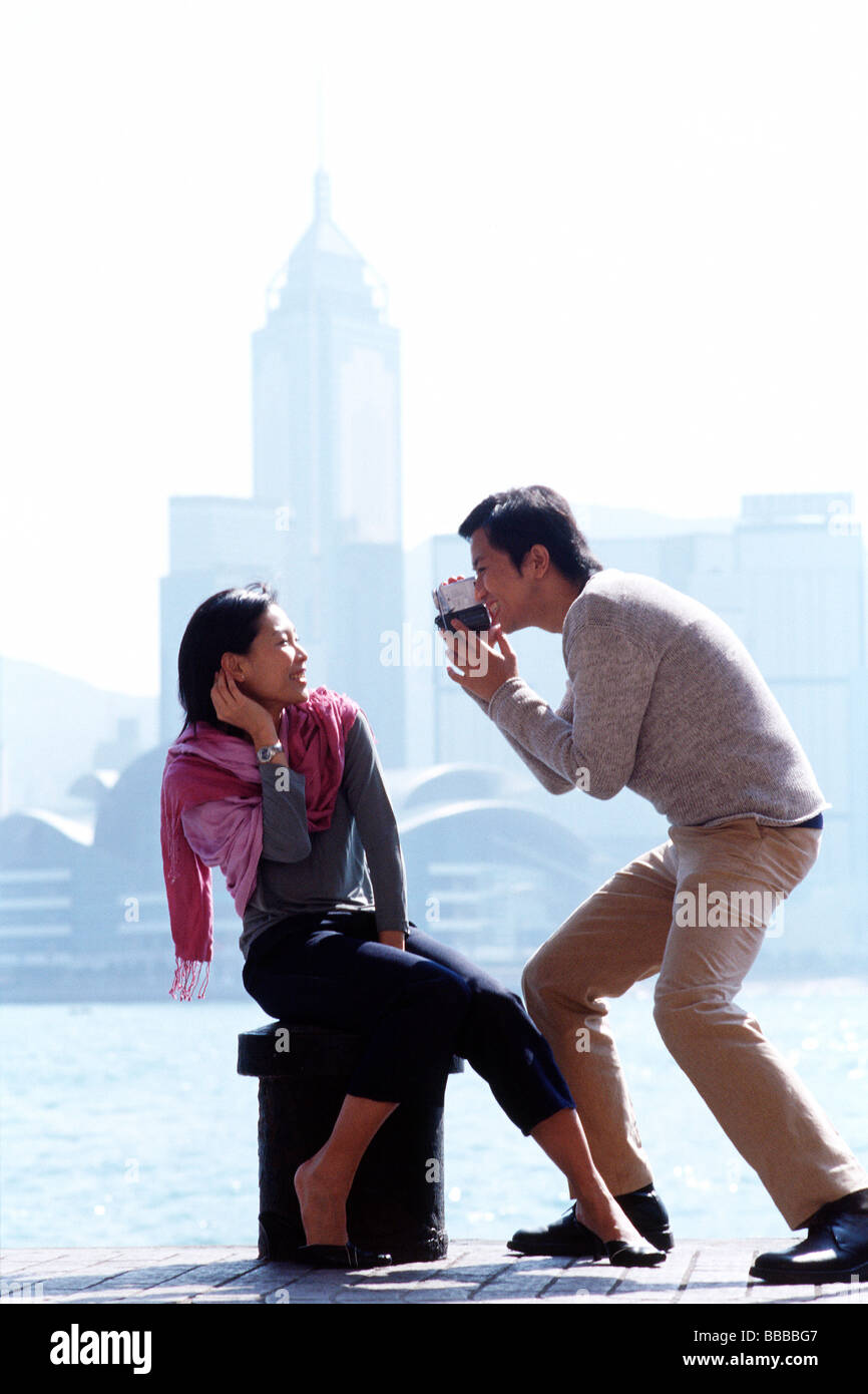 Couple by waterfront, man holding video camera Stock Photo - Alamy