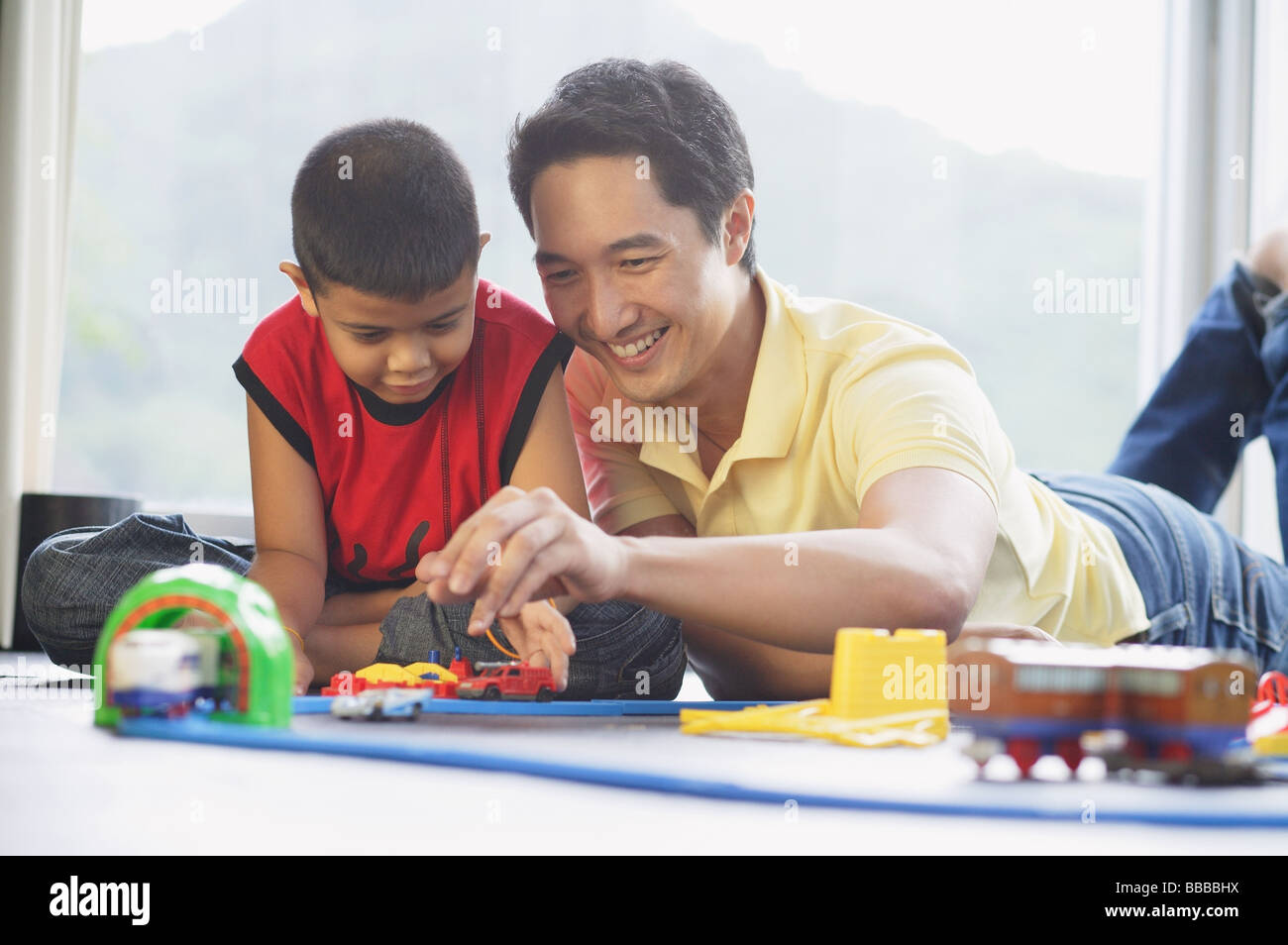 Father and son side by side on floor, playing with train set Stock ...