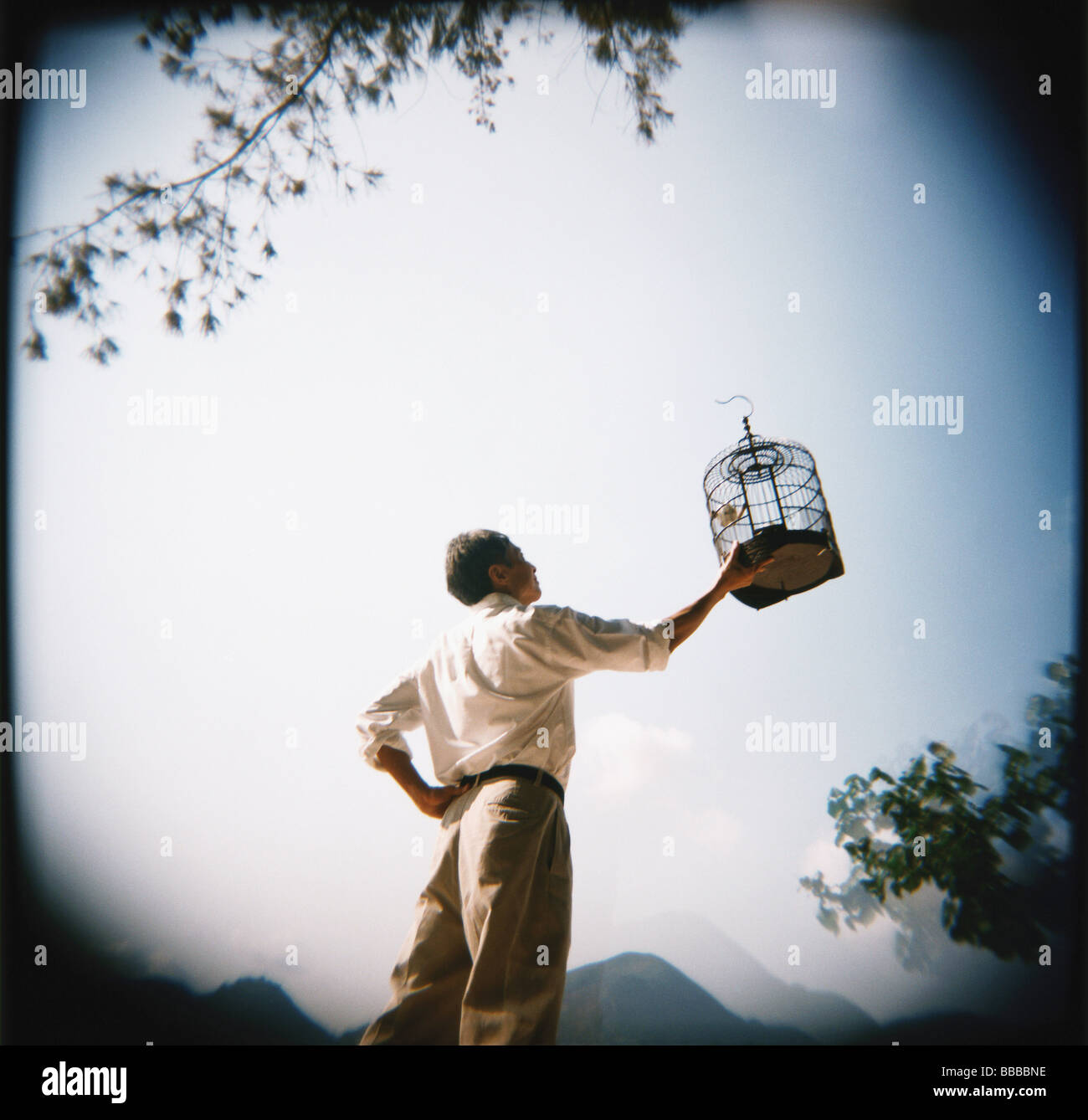 Man holding up birdcage Stock Photo - Alamy