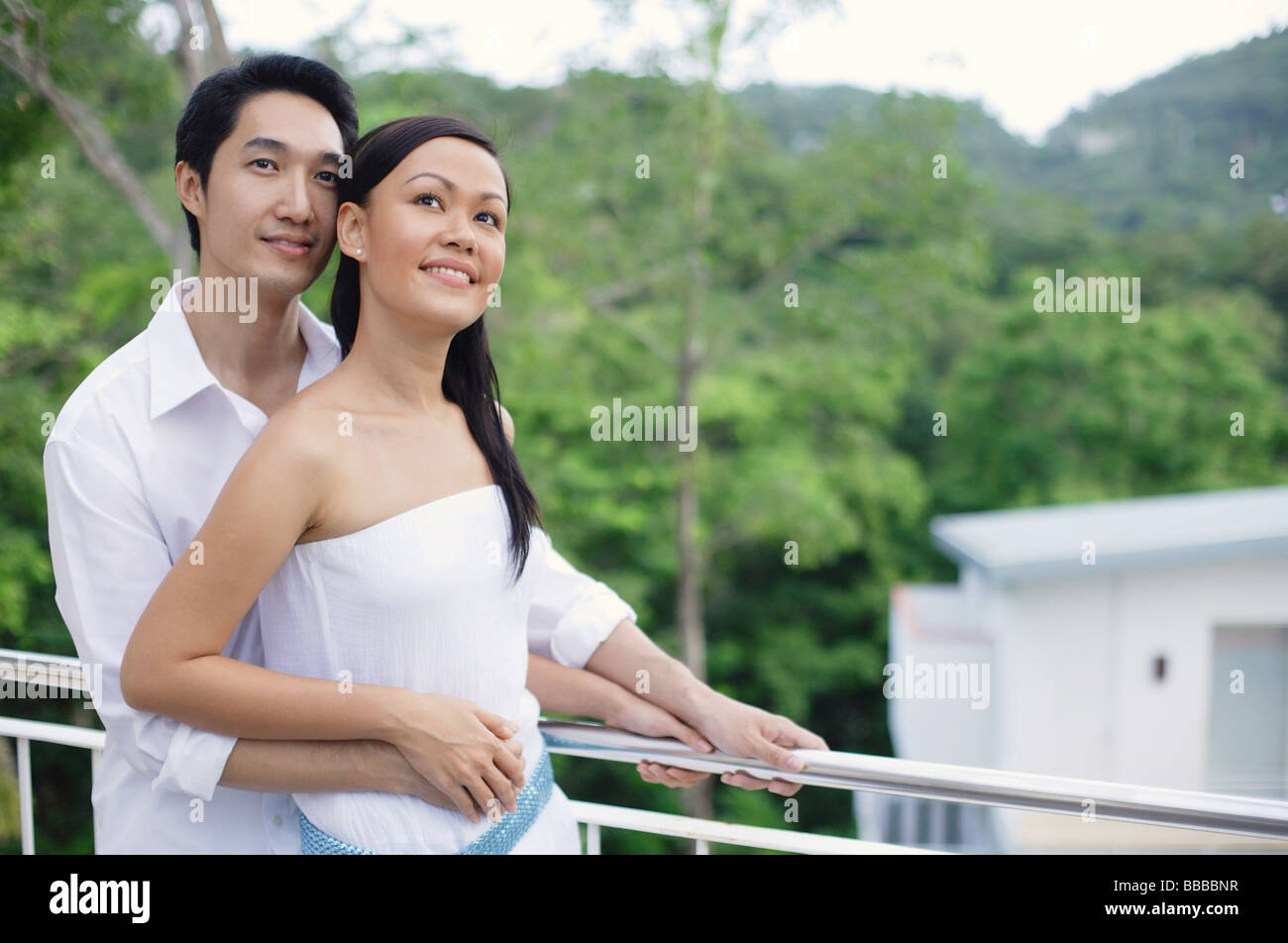 Couple next to railing, man embracing woman from behind Stock Photo - Alamy