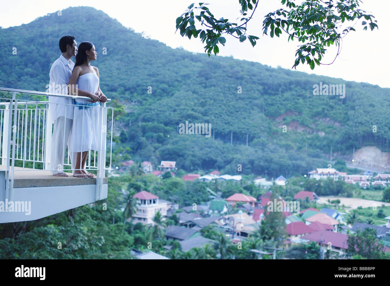 Couple standing on balcony looking out at view Stock Photo - Alamy