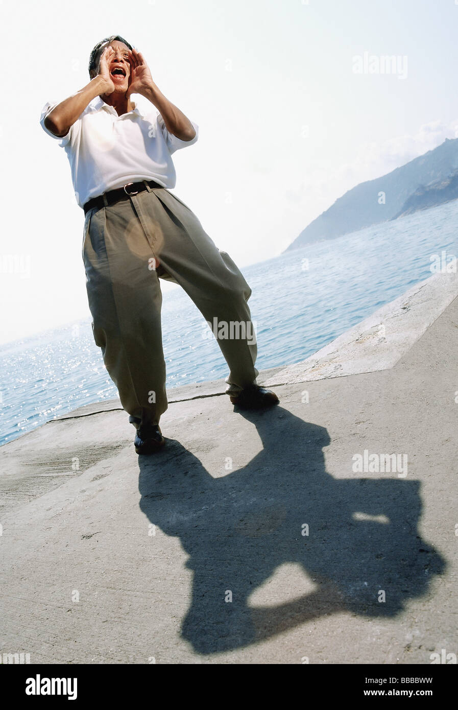 Man shouting on beach, sea in background Stock Photo - Alamy