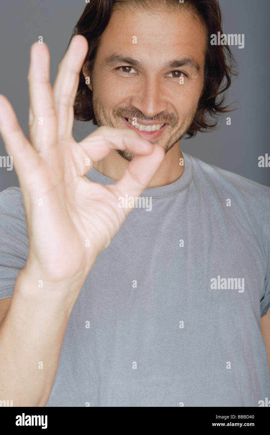Man looking at camera, making hand sign Stock Photo - Alamy