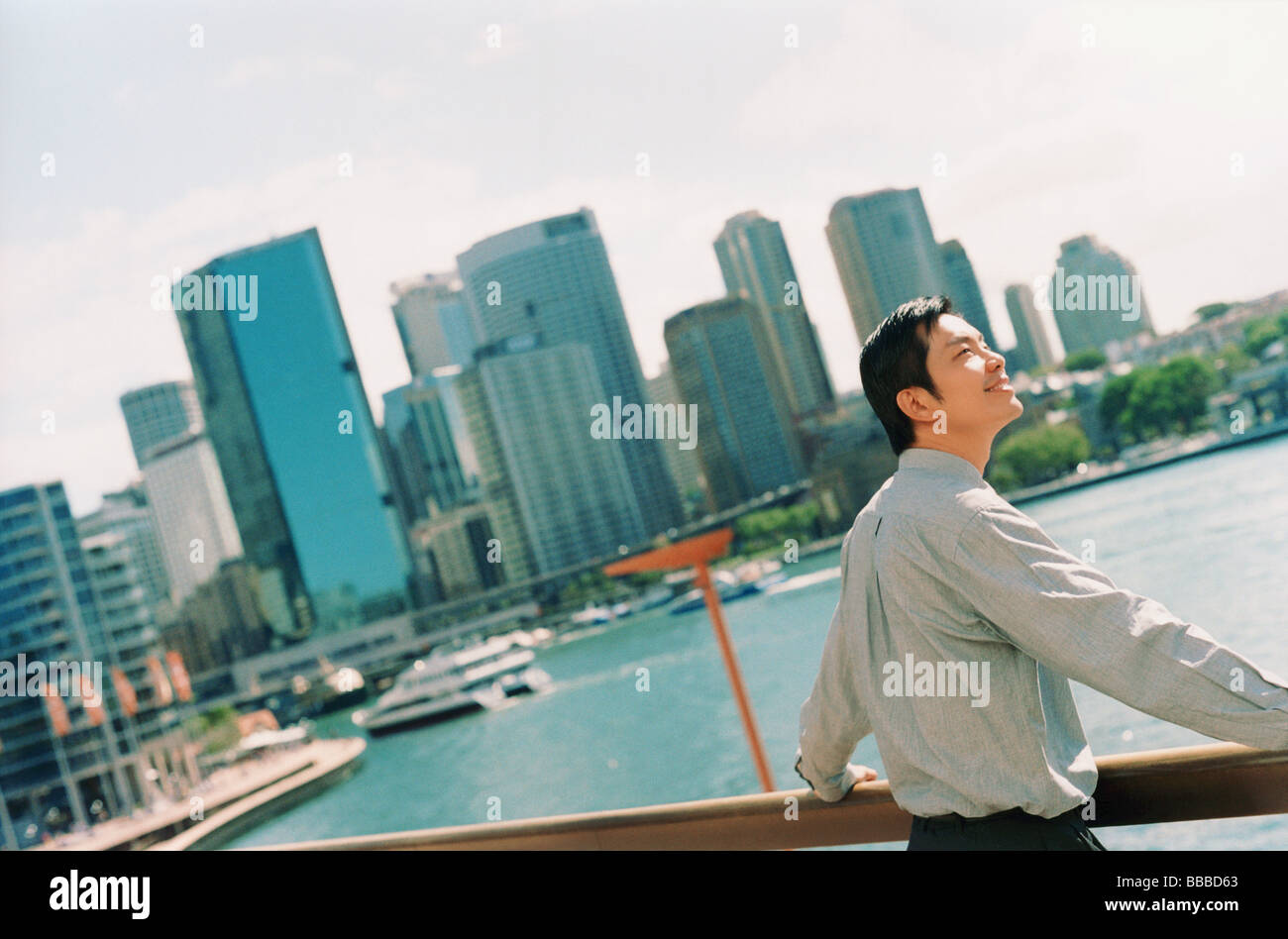 Man leaning on railing overlooking bay, skyline in background Stock ...