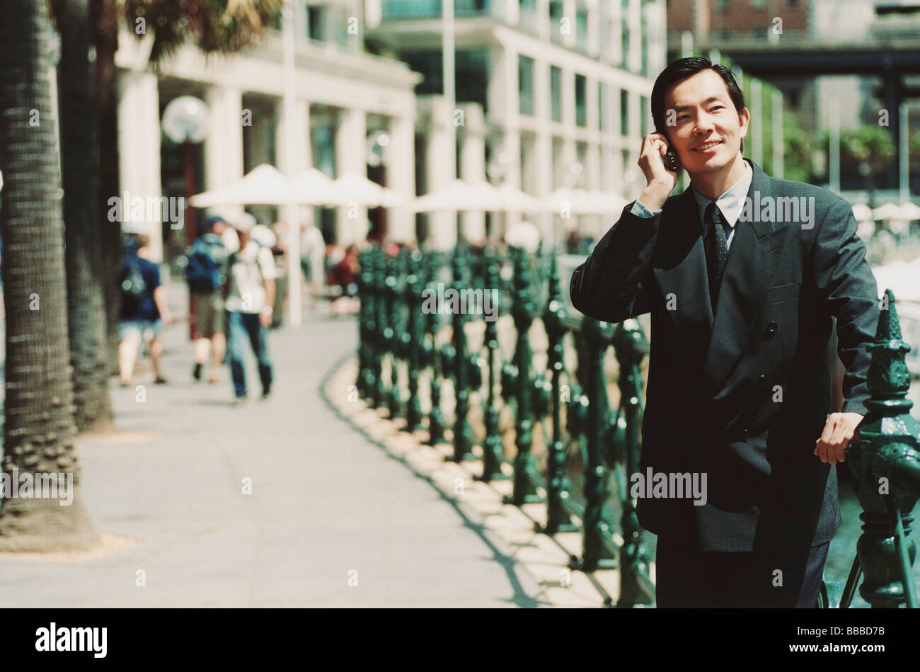 Executive using cellular phone, walkway in background Stock Photo - Alamy