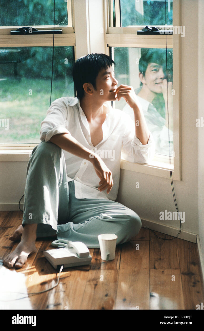 Man looking out window with chin on hand Stock Photo - Alamy