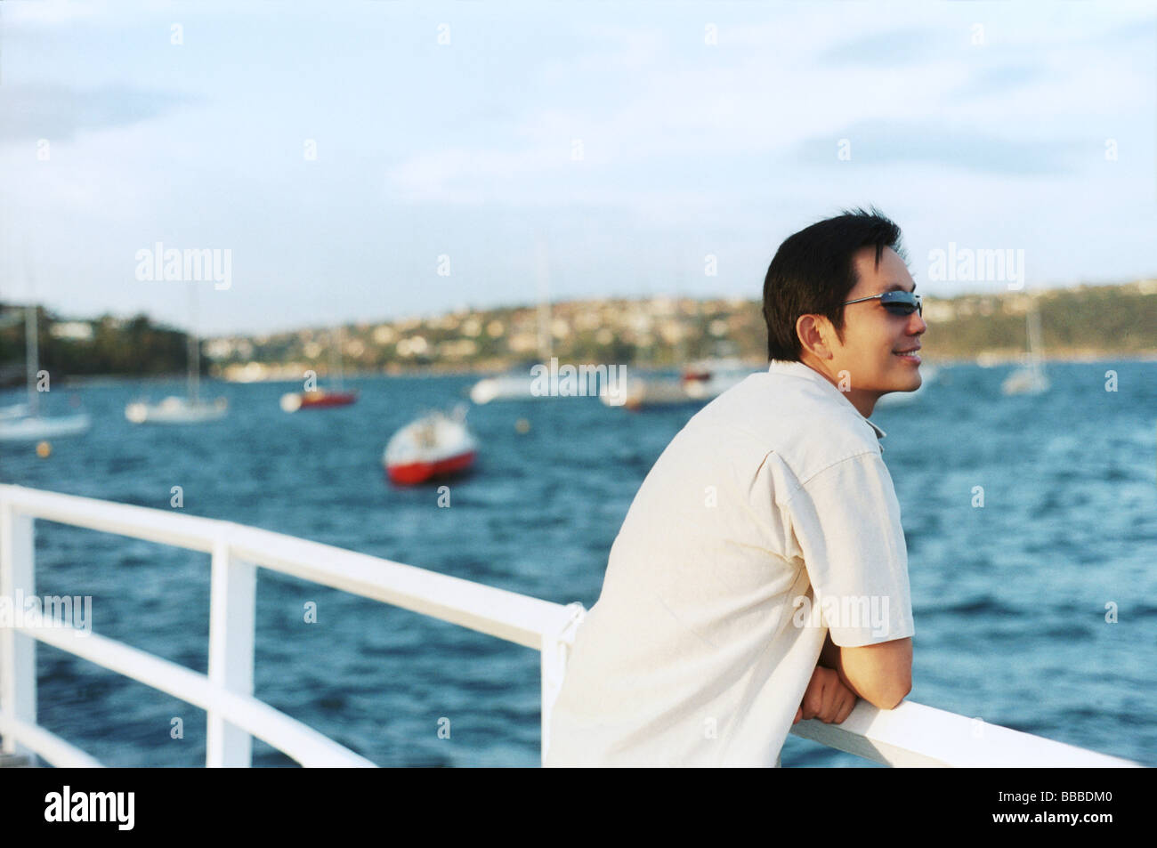 Man leaning on railing looking out at water Stock Photo - Alamy