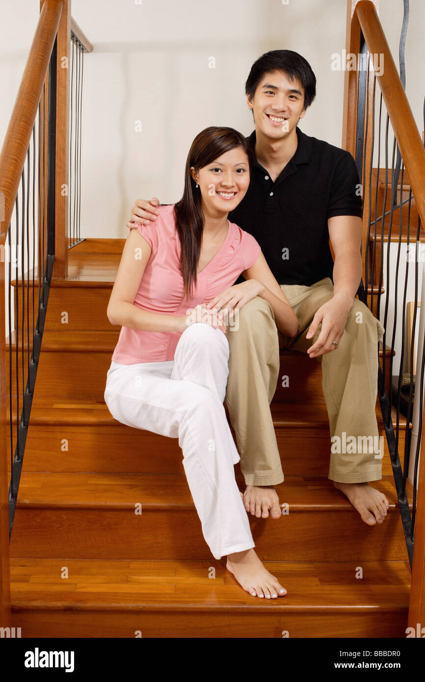 Couple sitting on stairs, looking at camera Stock Photo - Alamy
