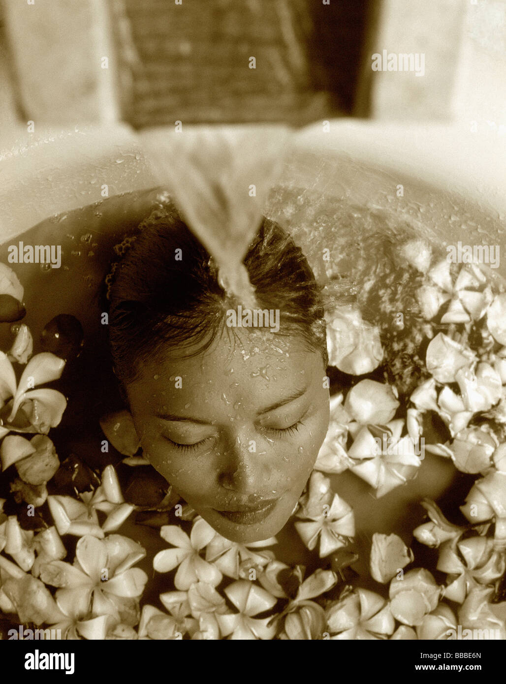 Woman in bath with floating flowers, head under running water Stock ...