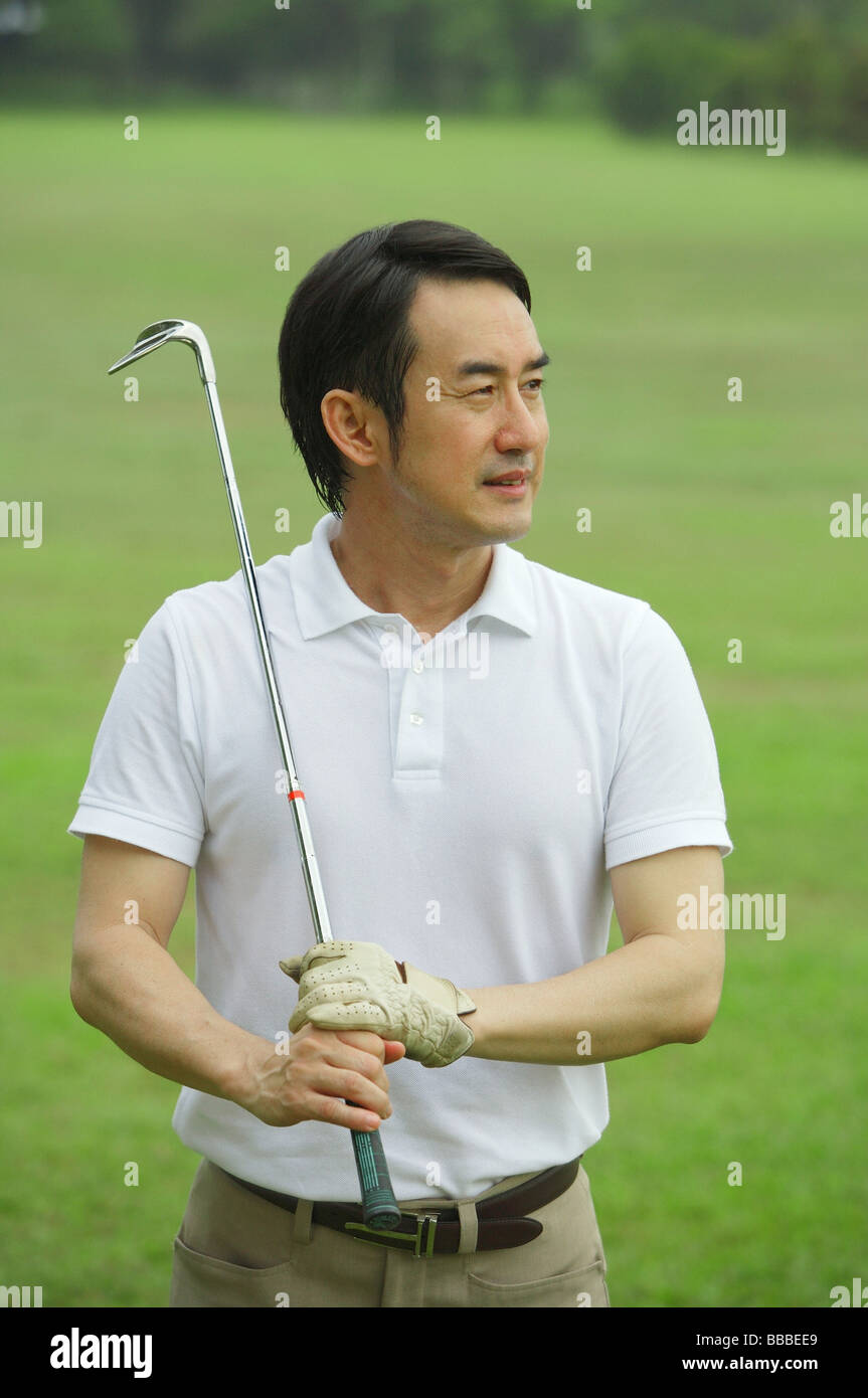 Man holding golf club, looking away Stock Photo - Alamy