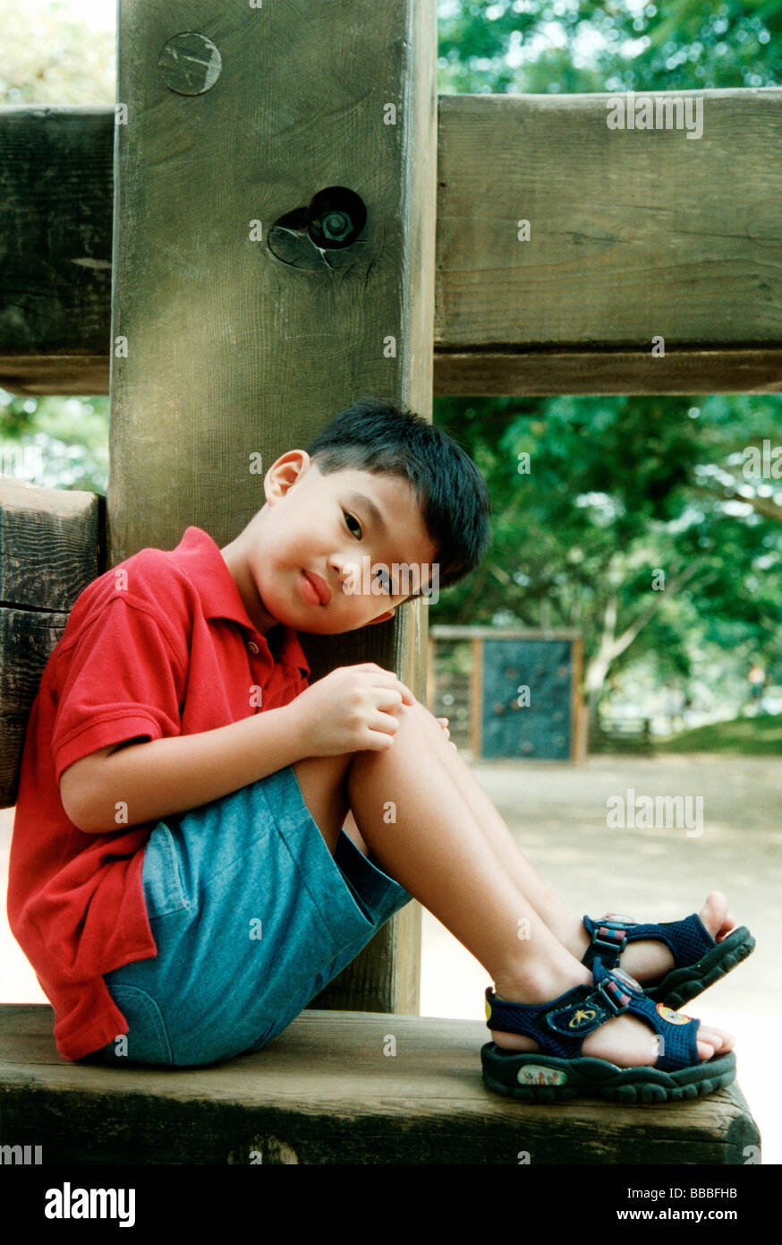 Young boy sitting in playground Stock Photo - Alamy