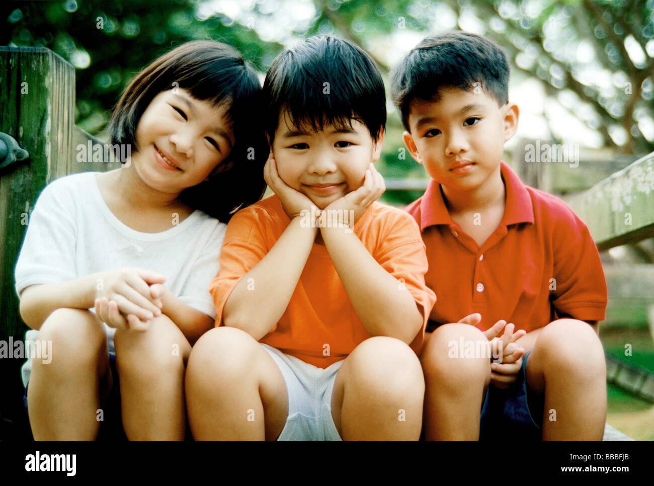 Three children sitting together Stock Photo - Alamy