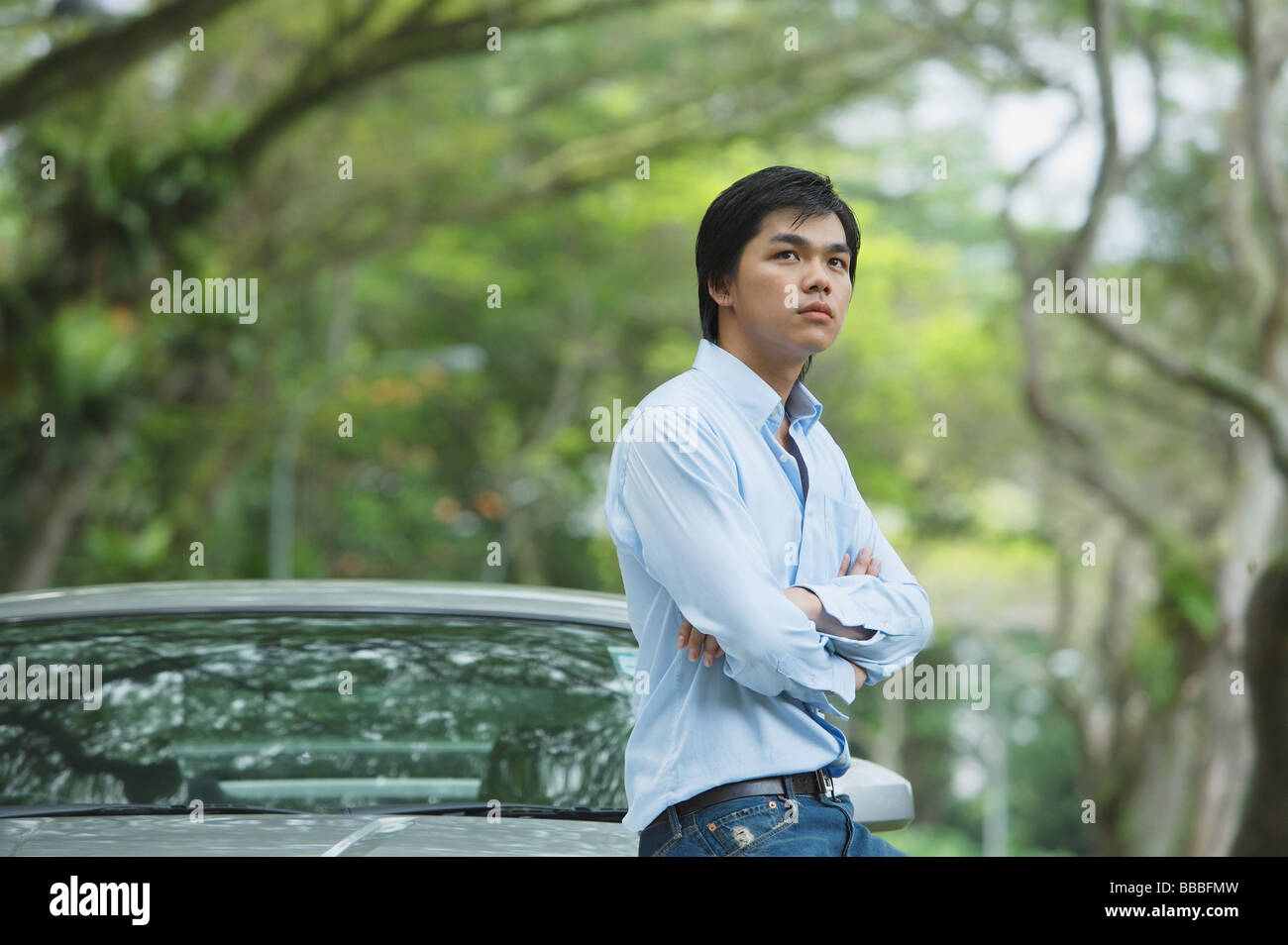 Man leaning on car, arms crossed Stock Photo - Alamy