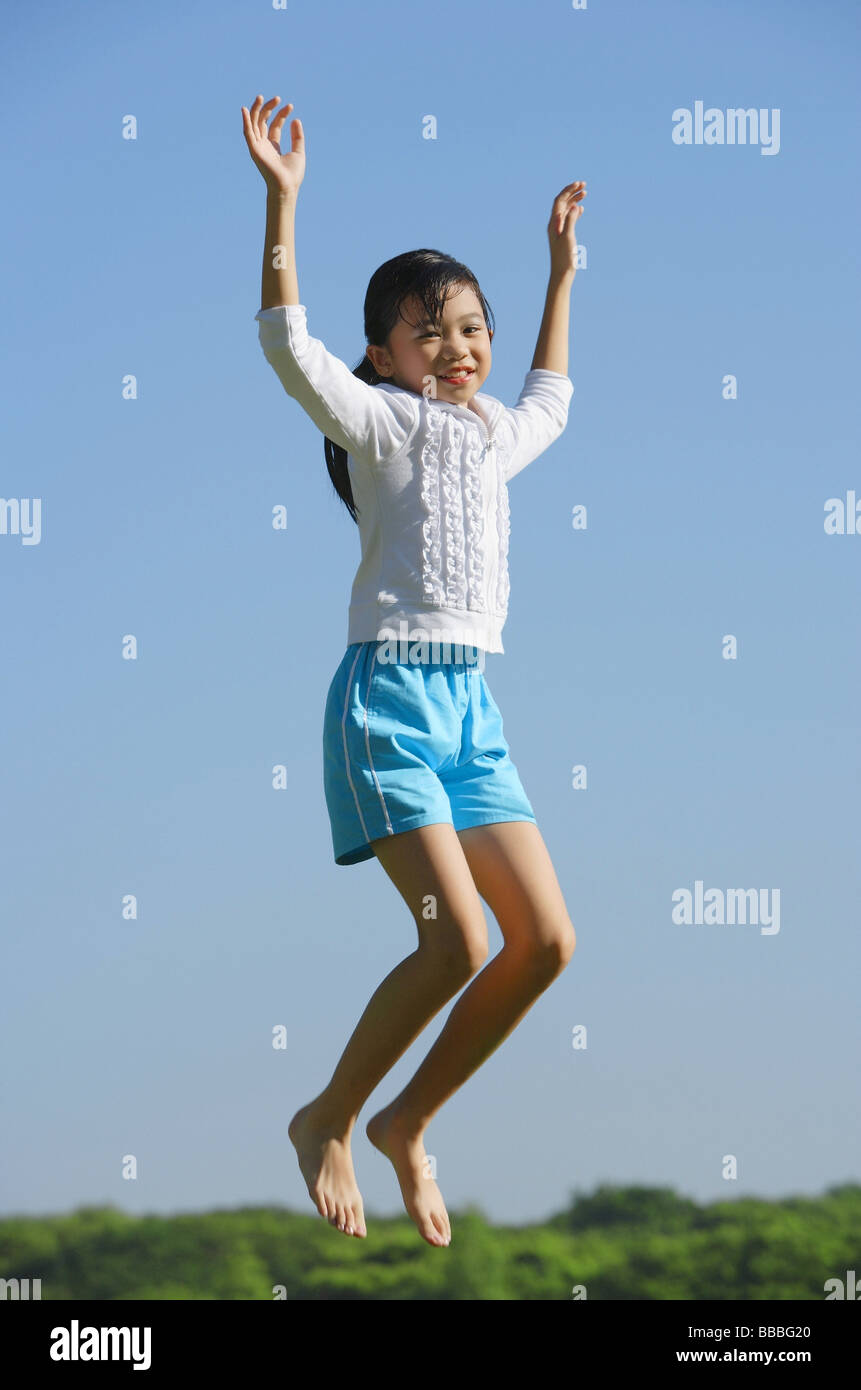 Girl jumping in mid air, smiling at camera Stock Photo - Alamy