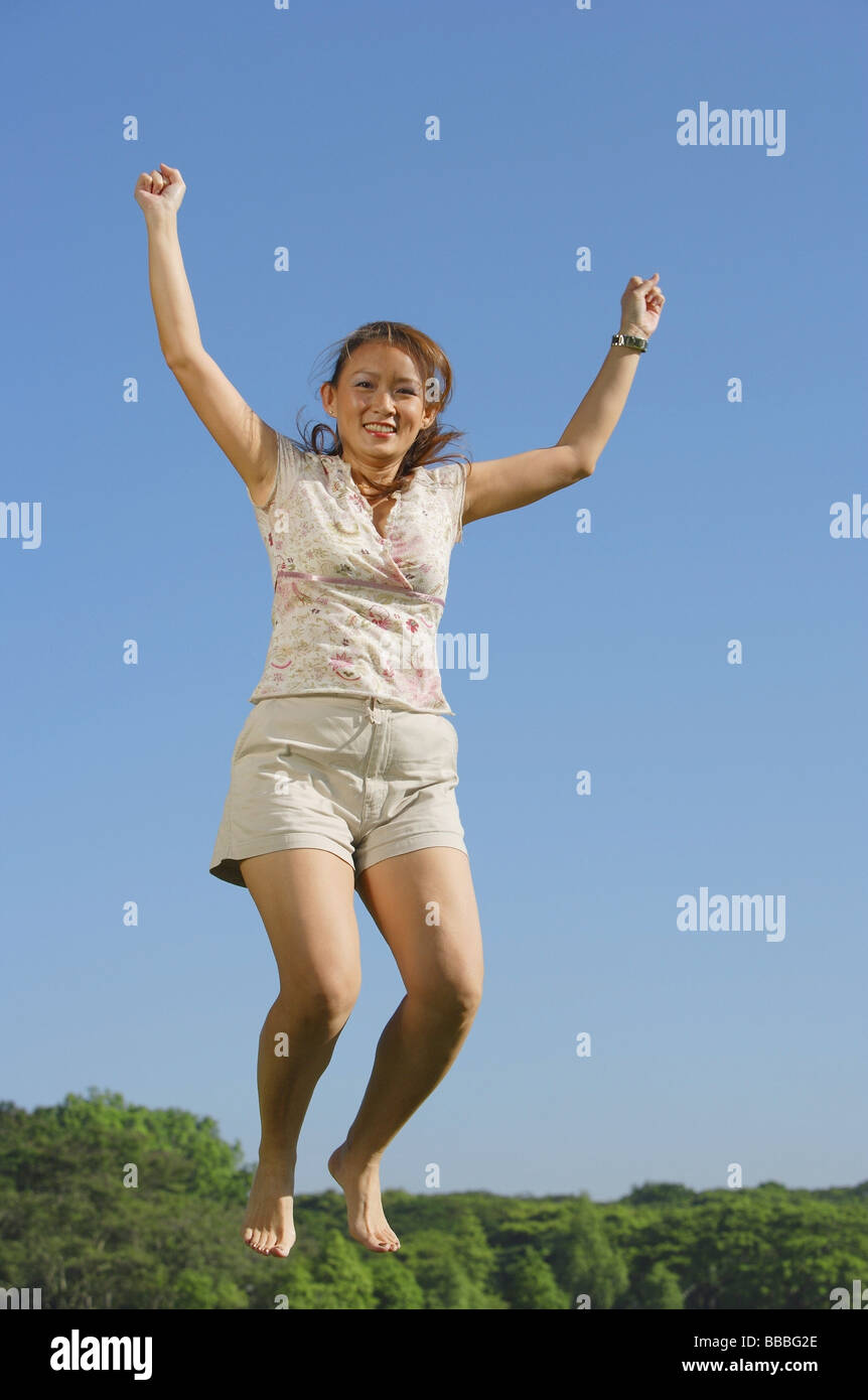 Woman jumping in mid air, smiling at camera Stock Photo - Alamy