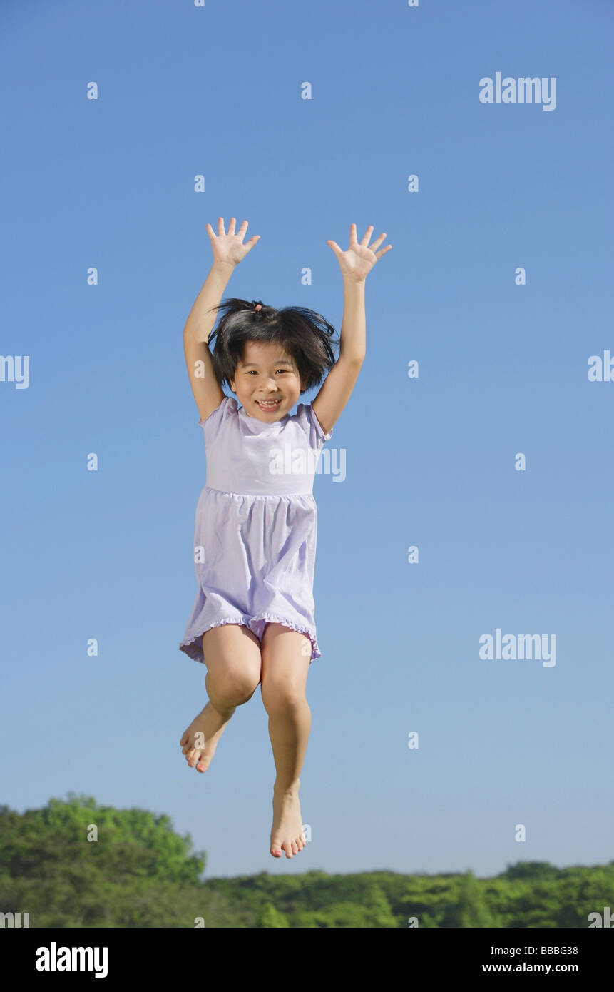 Girl jumping in mid air, arms outstretched, smiling Stock Photo - Alamy