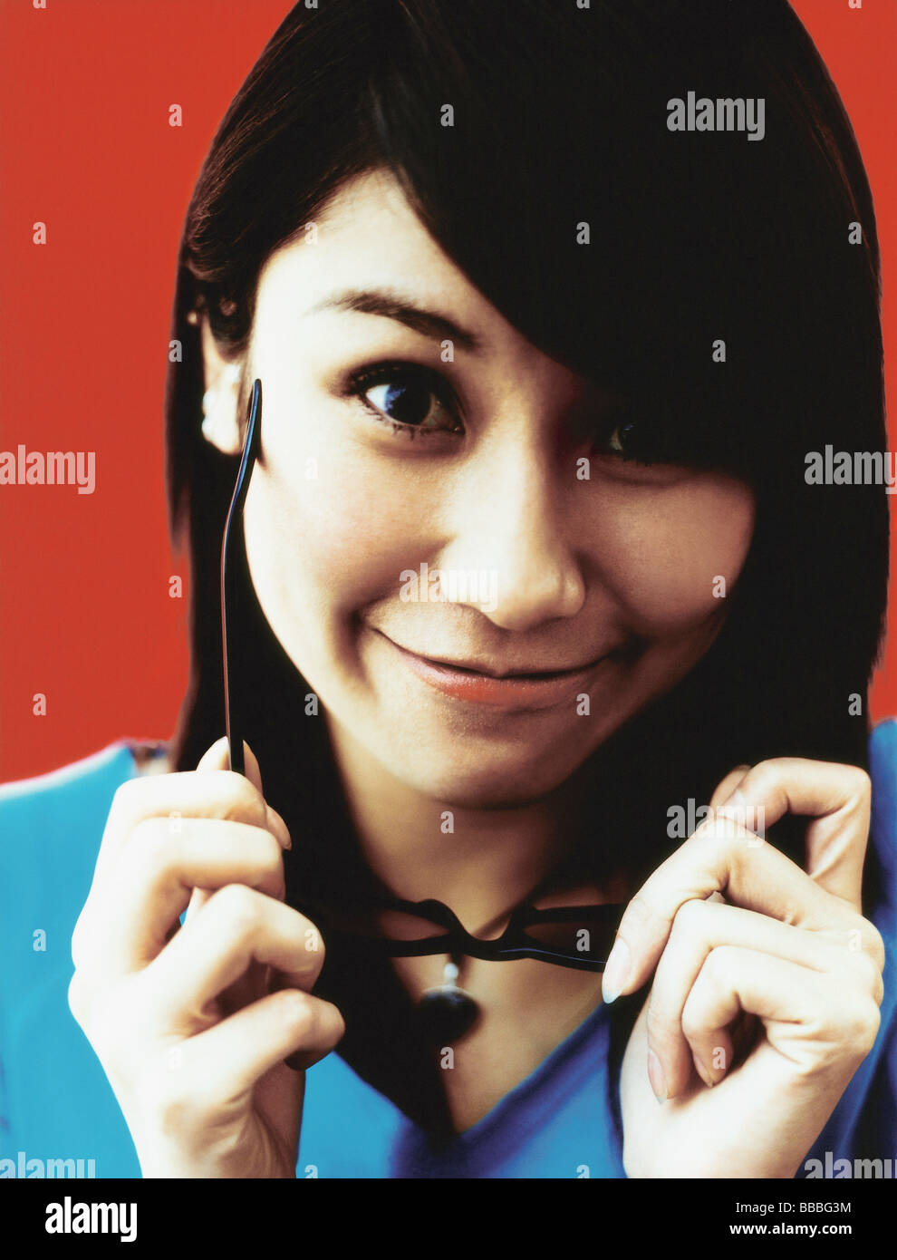 Young woman removing sunglasses, red background Stock Photo - Alamy