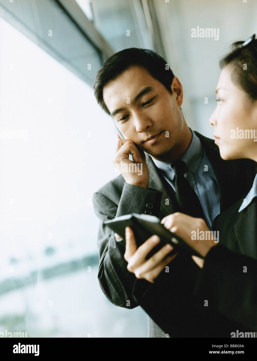 Executives using PDA and cellular phone Stock Photo - Alamy