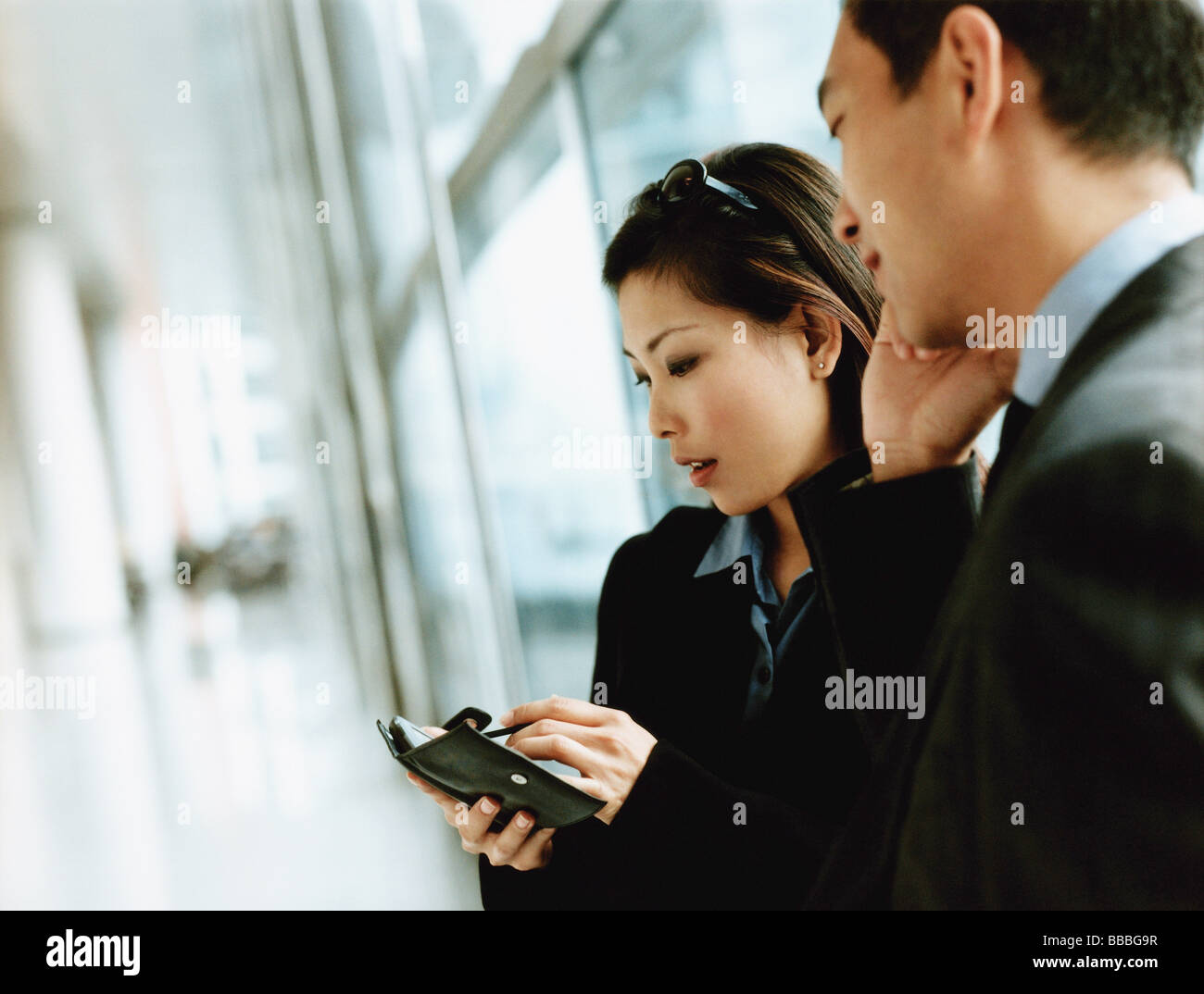 Executives using PDA and cellular phone Stock Photo - Alamy