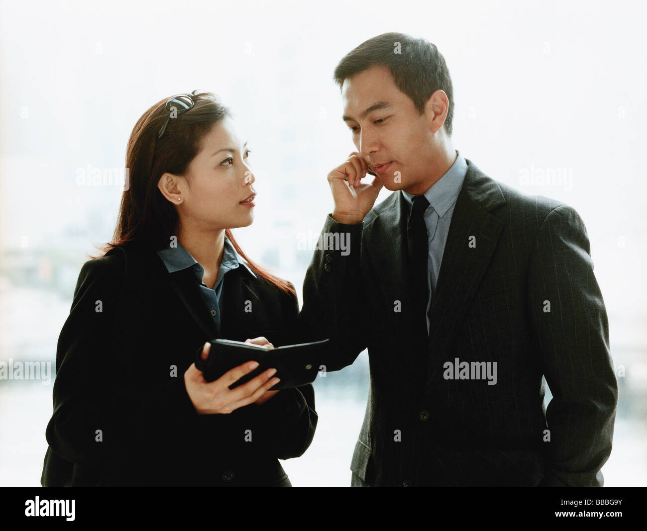 Executives using PDA and cellular phone Stock Photo - Alamy