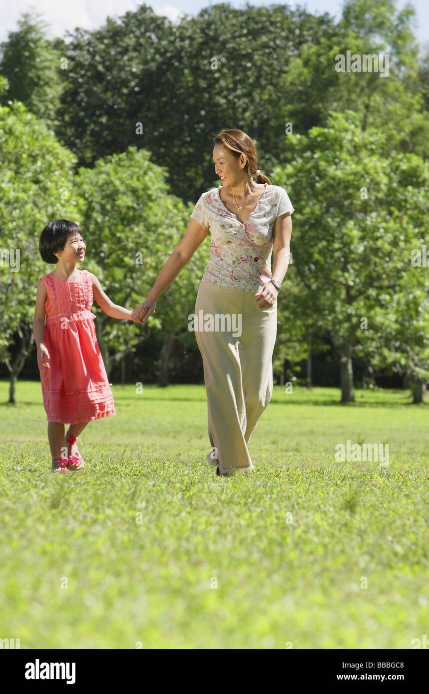 Mother and daughter, holding hands, walking on grass Stock Photo - Alamy