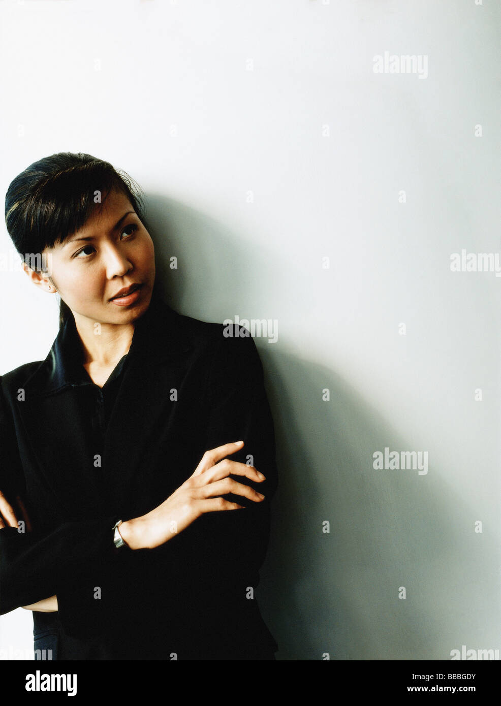 Female executive leaning against wall, looking off camera Stock Photo ...