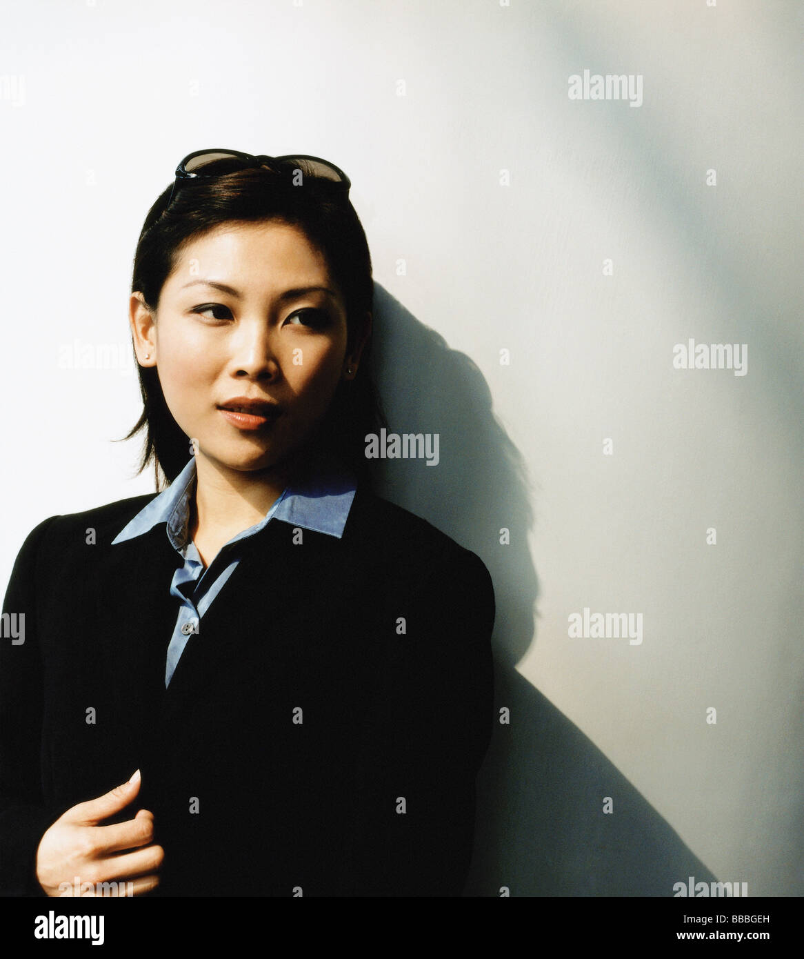 Female executive leaning against wall looking off camera Stock Photo ...