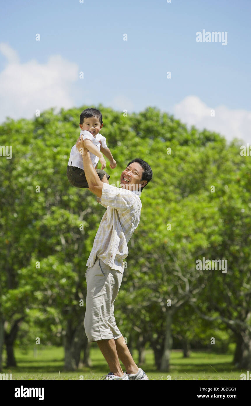 Father lifting son in the air, both looking at camera Stock Photo - Alamy