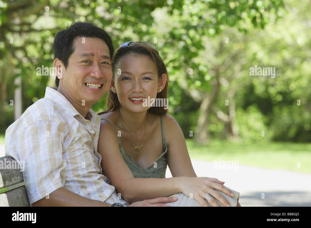 Couple sitting on bench, looking at camera Stock Photo - Alamy